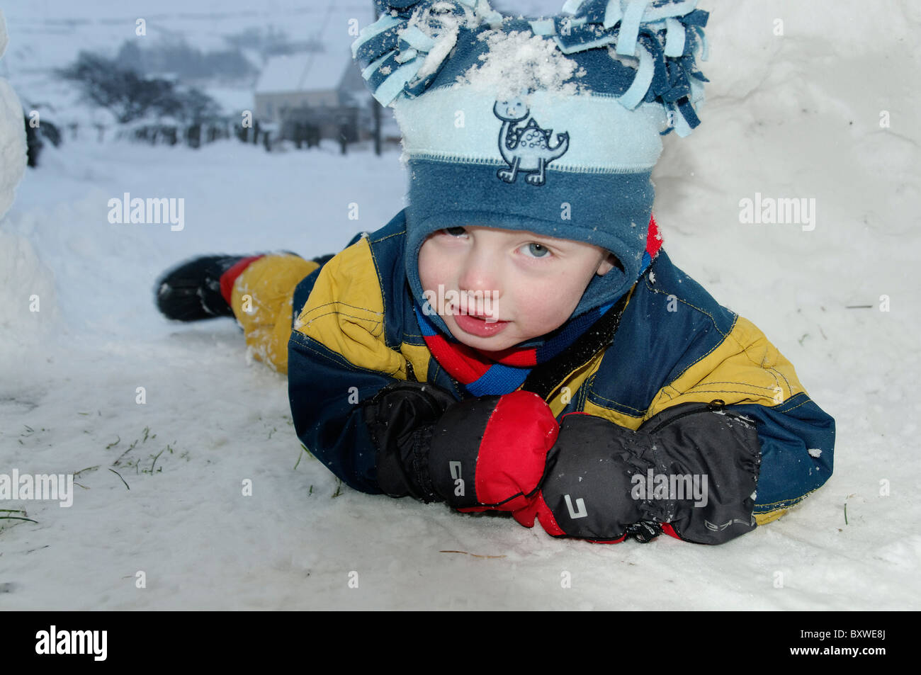 A young boy crawling into a snow cave in a garden Stock Photo - Alamy