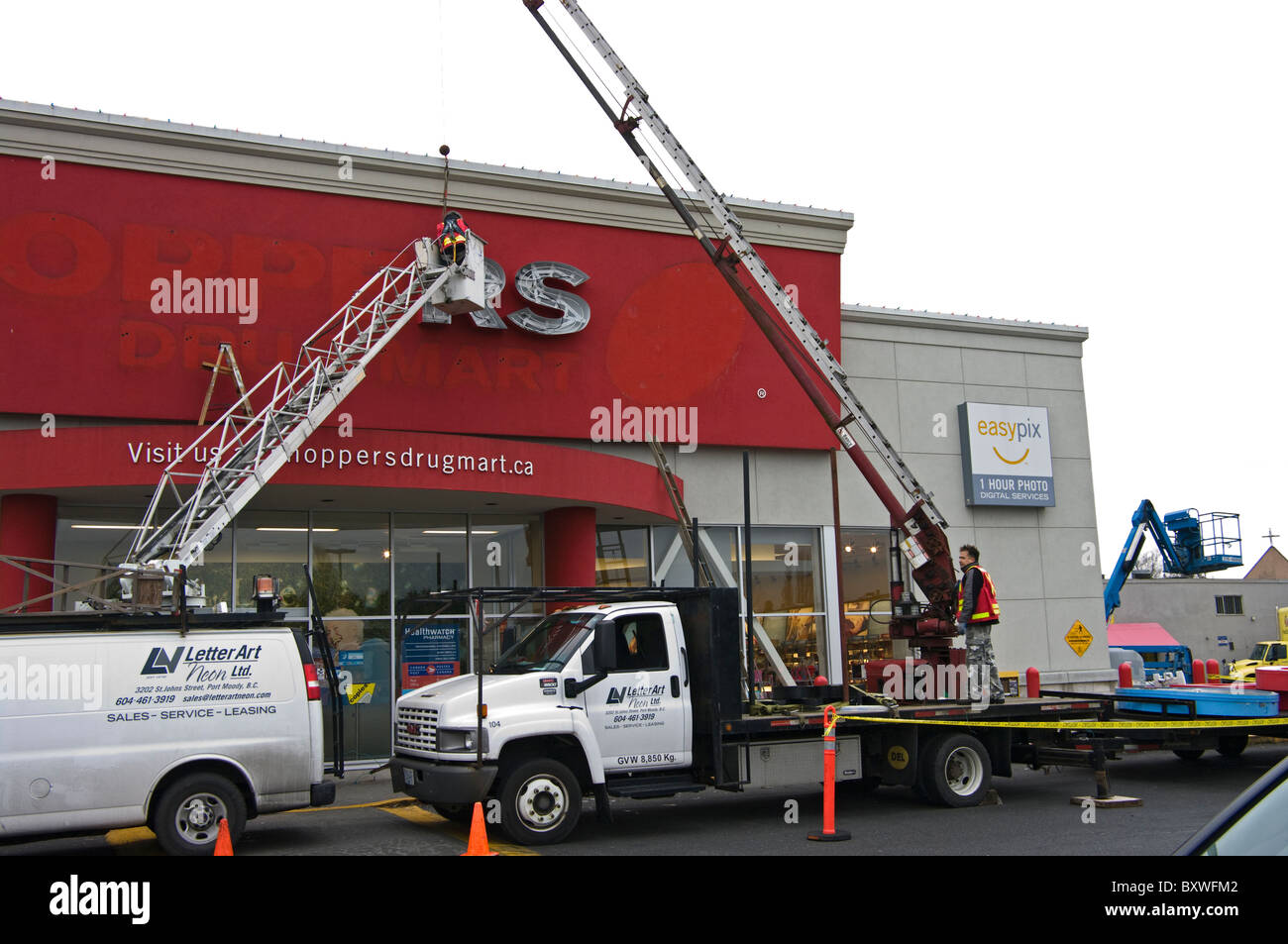 Work crew with crane removing neon signs from store frontage Stock ...