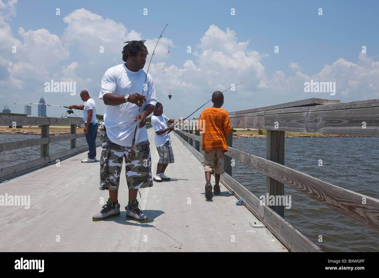 USA, Alabama, Mobile, African-American families fishing from dock along ...