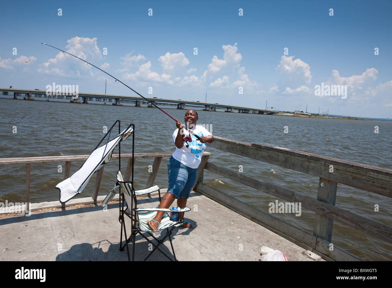 USA, Alabama, Mobile, African-American woman casts while fishing in ...
