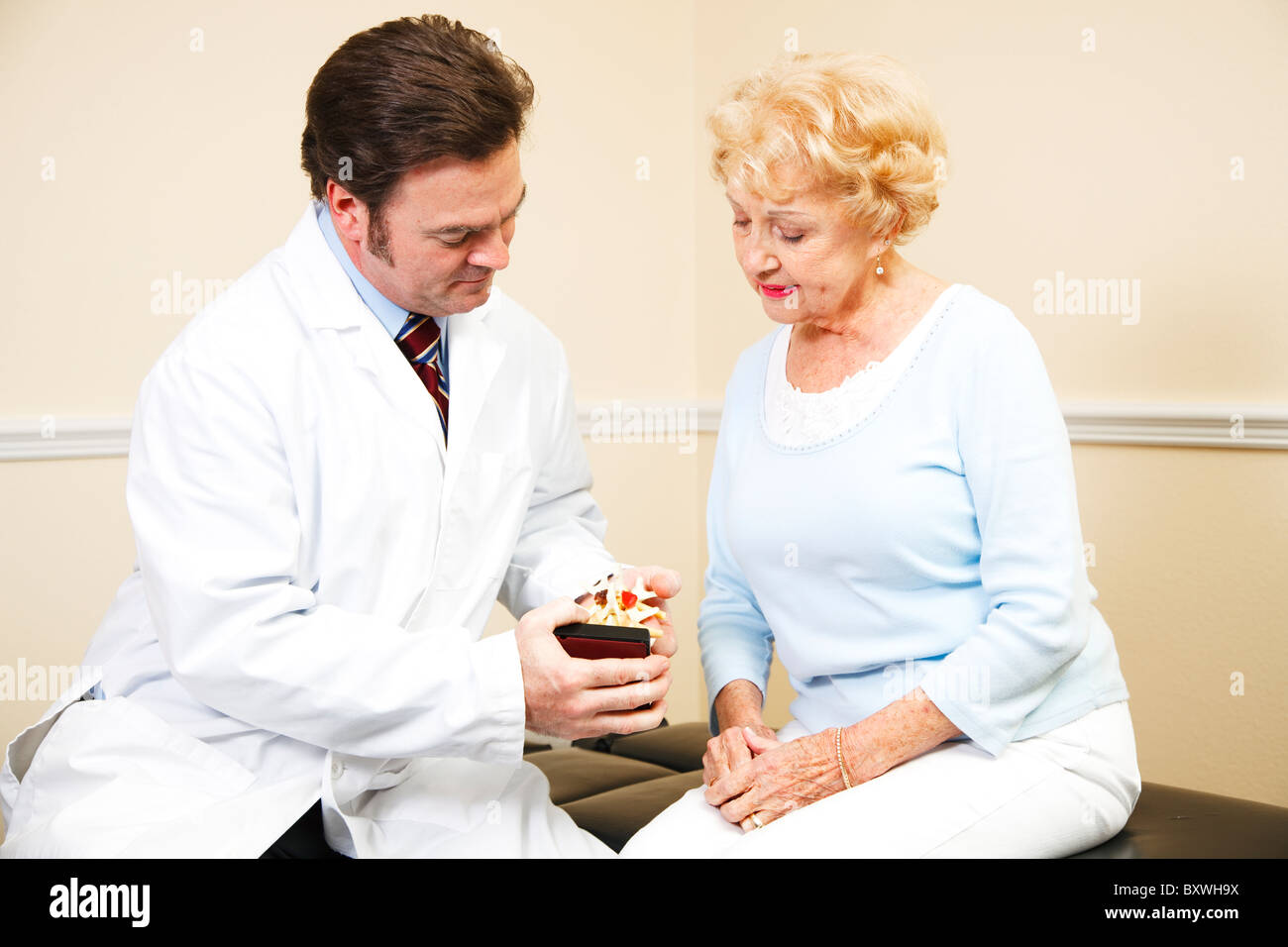 Chiropractor uses a model of the human spine to explain treatment to a ...