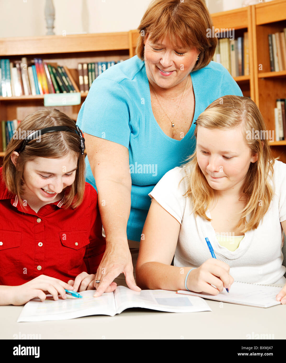 Teacher or librarian in the school library, helping teenage students ...