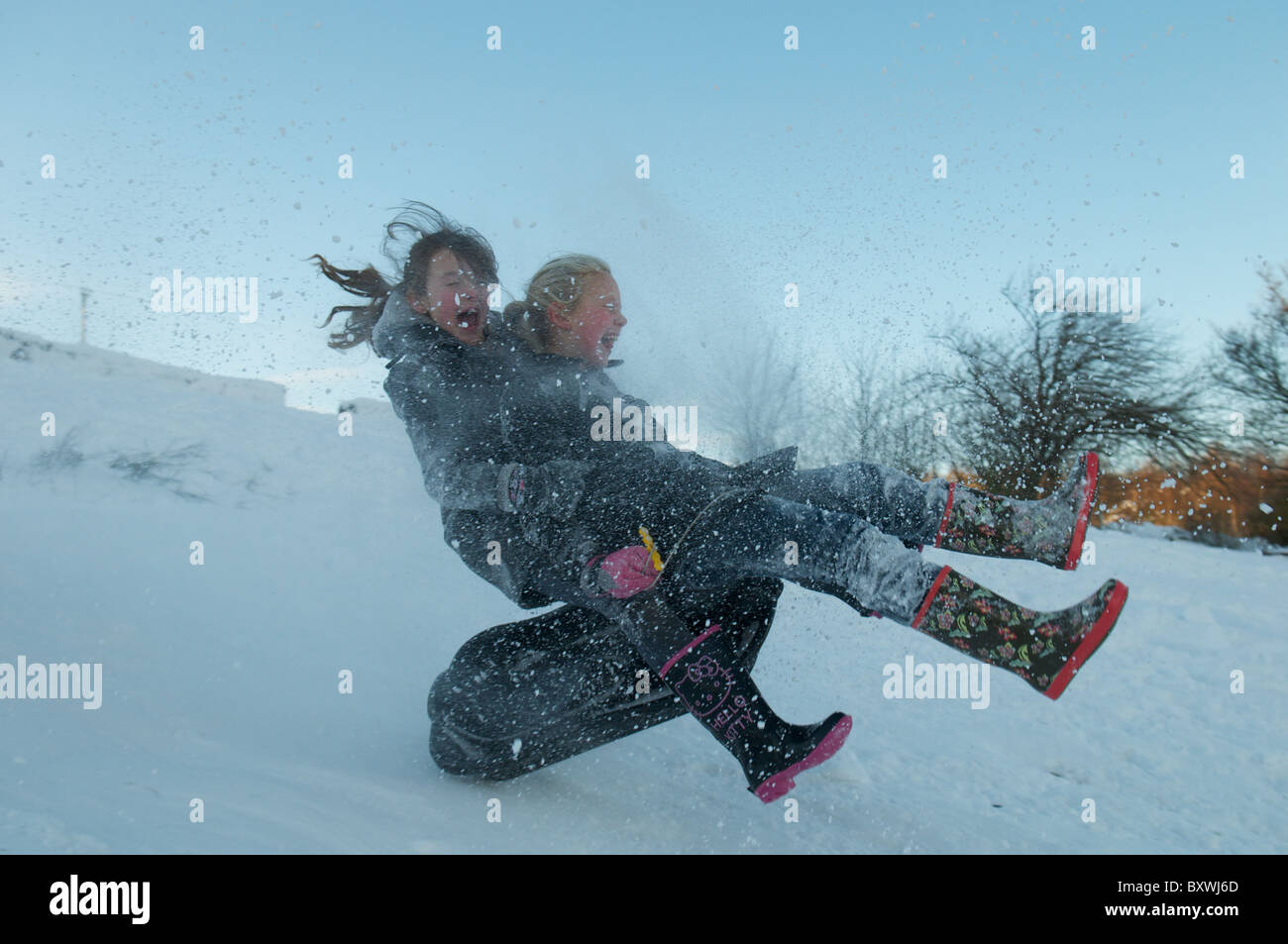 Young girls flying through the air on a sled Stock Photo - Alamy