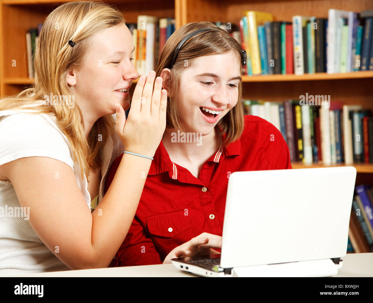 Teen girls browsing the internet on the school computer and whispering ...