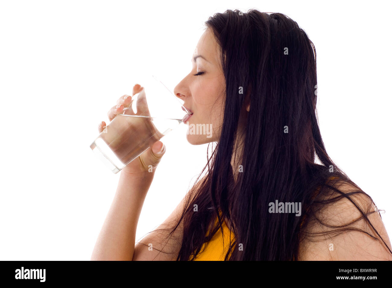 Thirsty young woman drinking a glass of fresh cold water isolated over ...