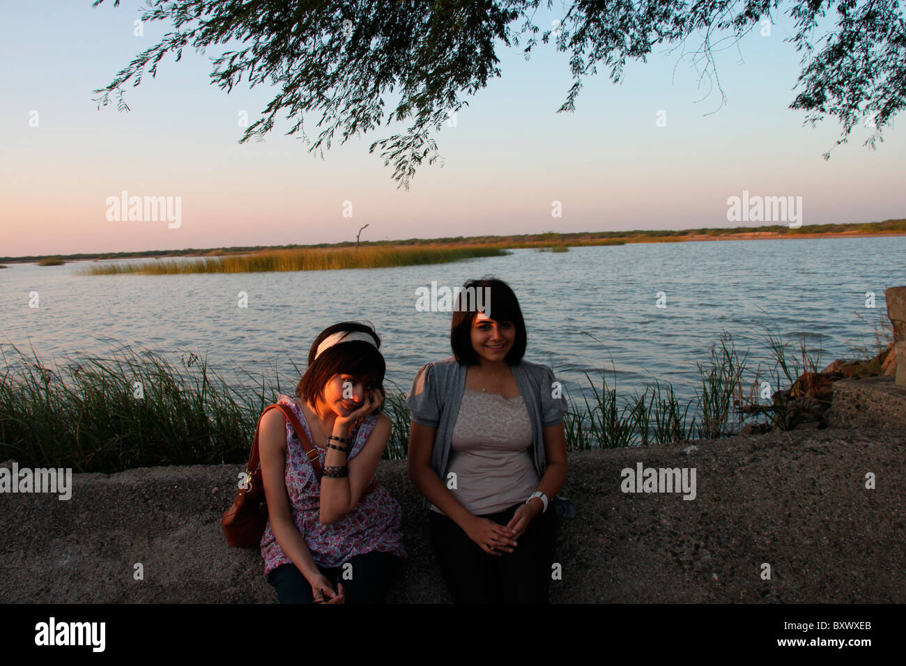 Two Indian girls relaxing near a pond during sunset time Stock Photo ...