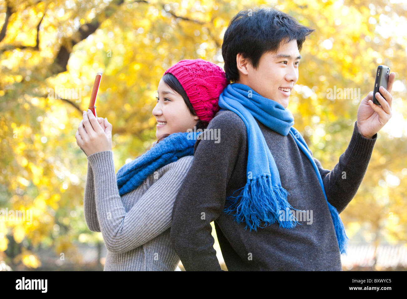 Young Couple Text Messaging Back-To-Back Stock Photo - Alamy