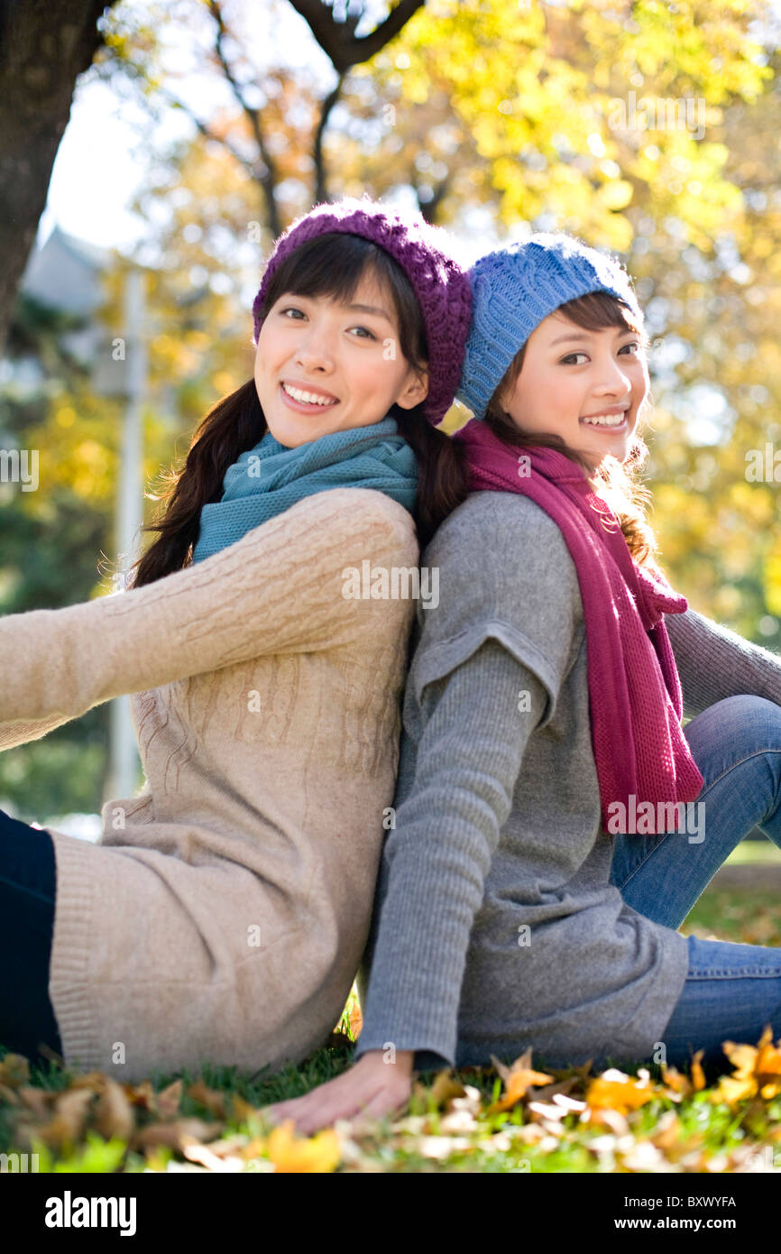 Friends Sitting Back To Back in a Park Stock Photo - Alamy