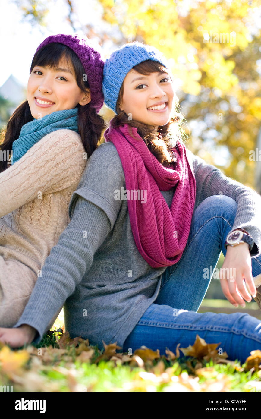 Friends Sitting Back To Back in a Park Stock Photo - Alamy