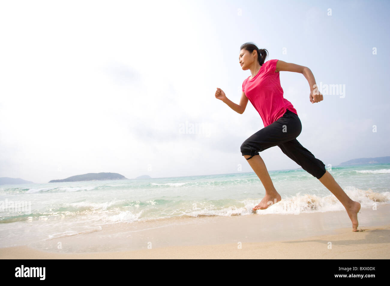 Young woman running on the beach Stock Photo - Alamy