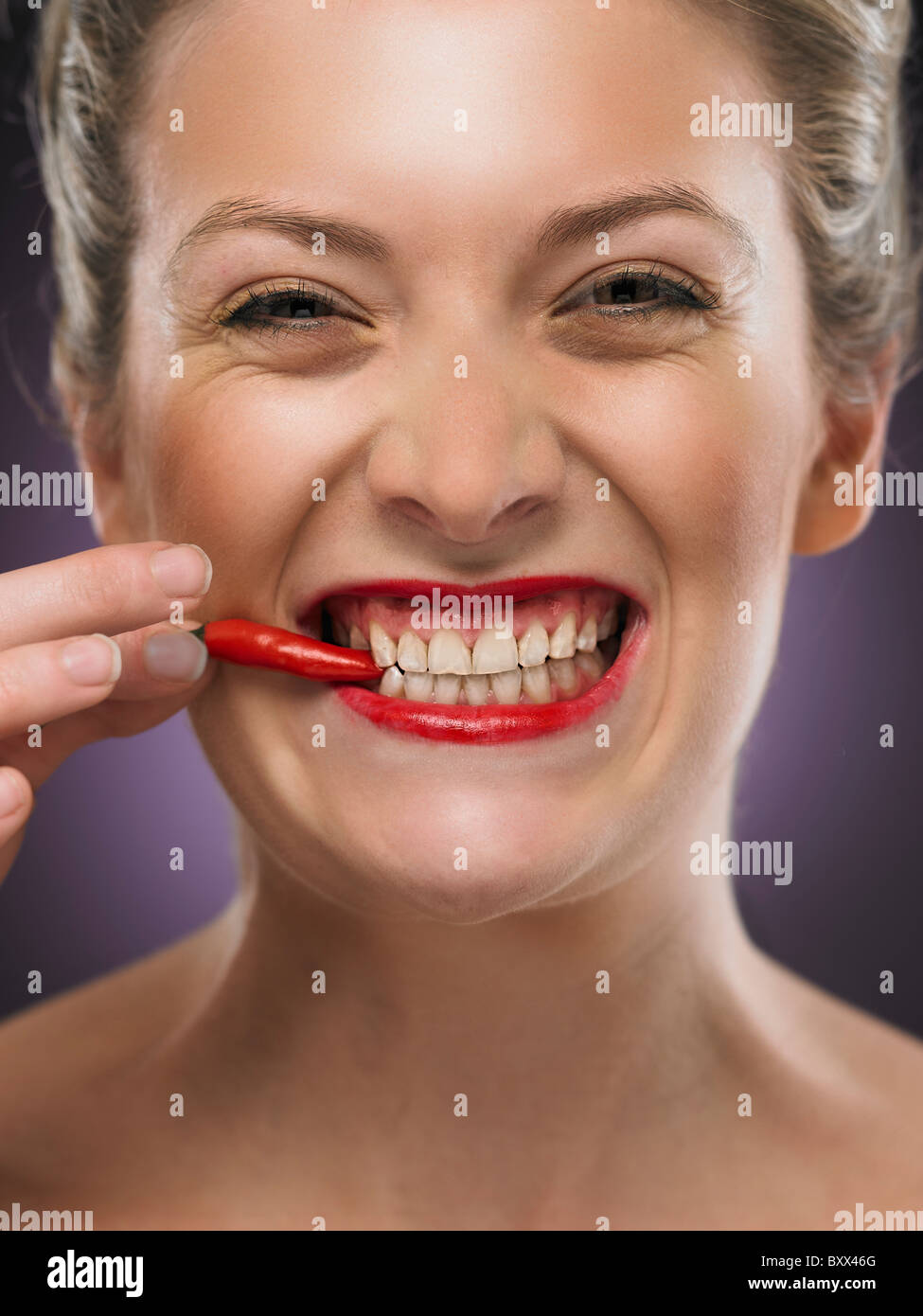 white blonde woman biting a chili pepper Stock Photo - Alamy