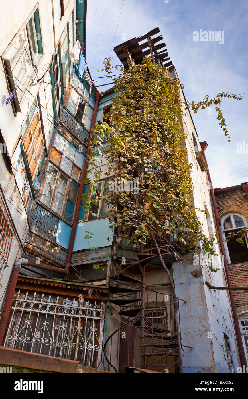 Overgrown external metal spiral staircase on building in Tbilisi old ...