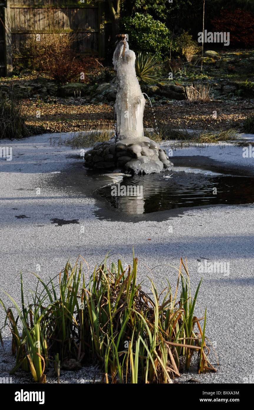 Frozen pond and frozen statue of woman with pitcher, English winter ...