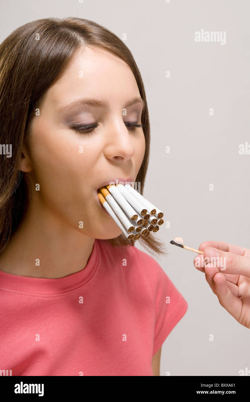 Woman with multiple cigarettes in mouth, hand holding match Stock Photo ...