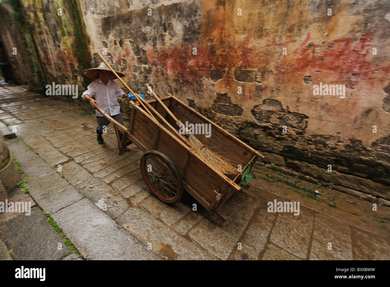Chinese man pushing cart on narrow streets of Hong Cun Village, Yi ...