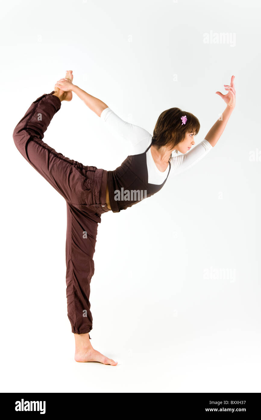 Portrait of a young pretty girl standing on one leg and holding another ...