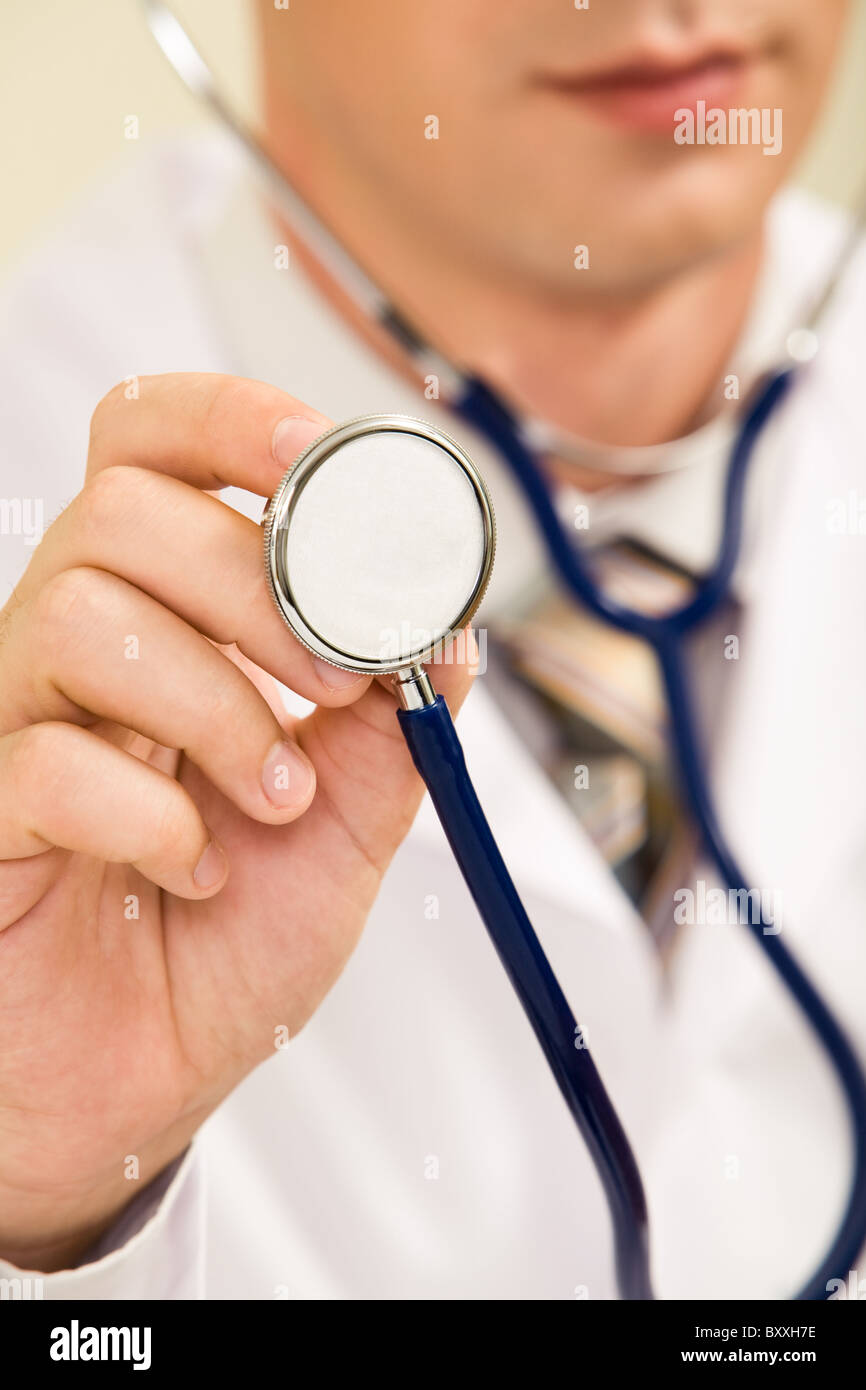 Close-up of male doctor’s hand holding stethoscope with man on ...