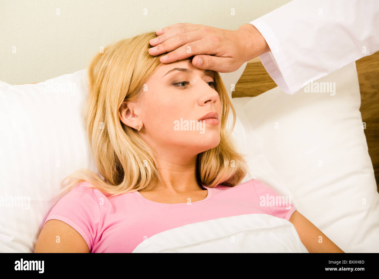 Close-up of ill woman in bed with doctor’s hand on her forehead Stock ...