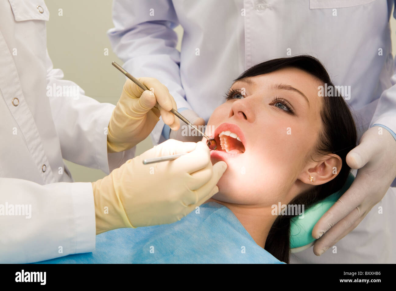 Photo of female patient with open mouth while her teeth being examined ...