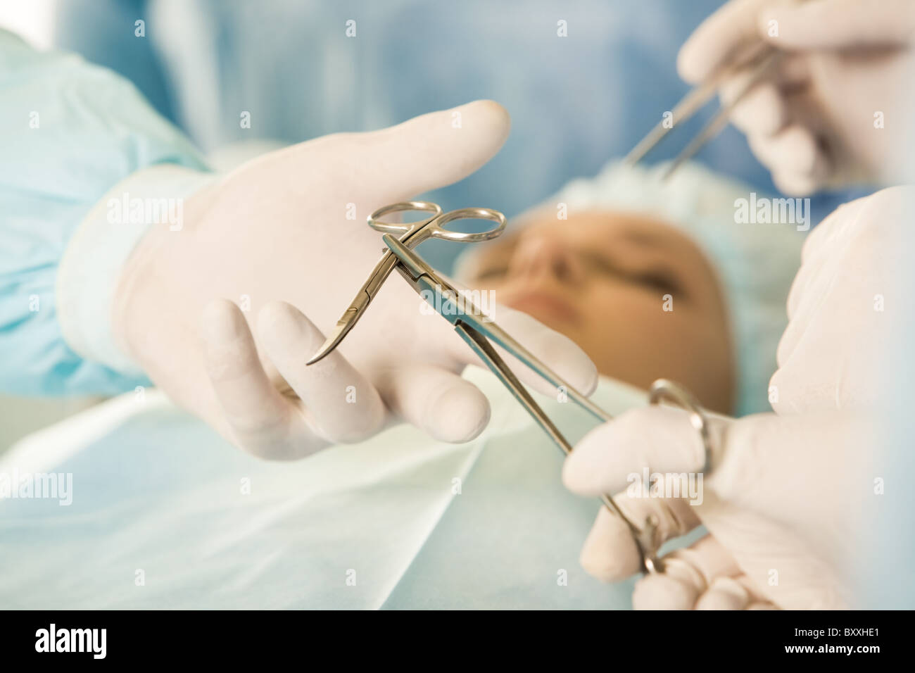 Close-up of medical instrument being passed over by assistant to ...
