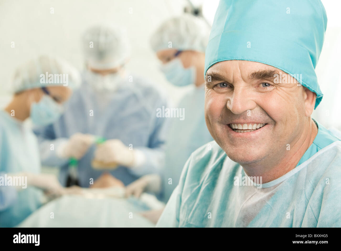 Portrait of happy doctor on background of working surgeons Stock Photo ...