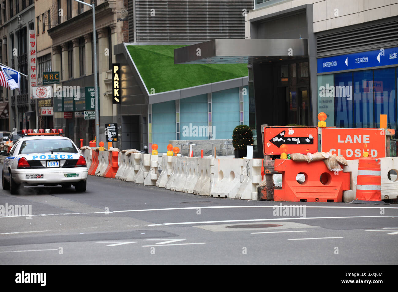 Police car entering street with lane closed barricade at construction ...