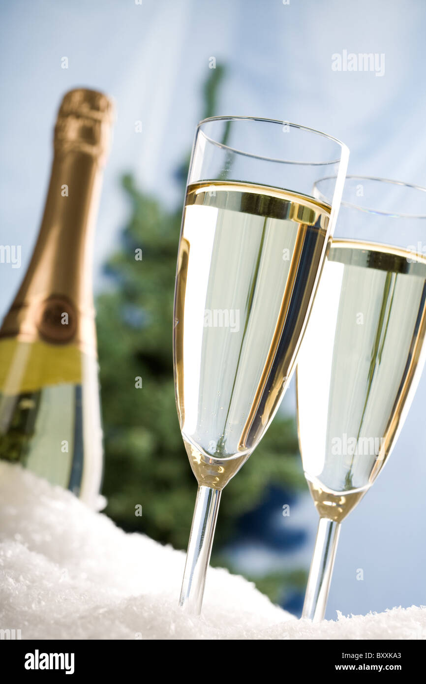 Close-up of full champagne flutes cooling in snow with bottle at ...