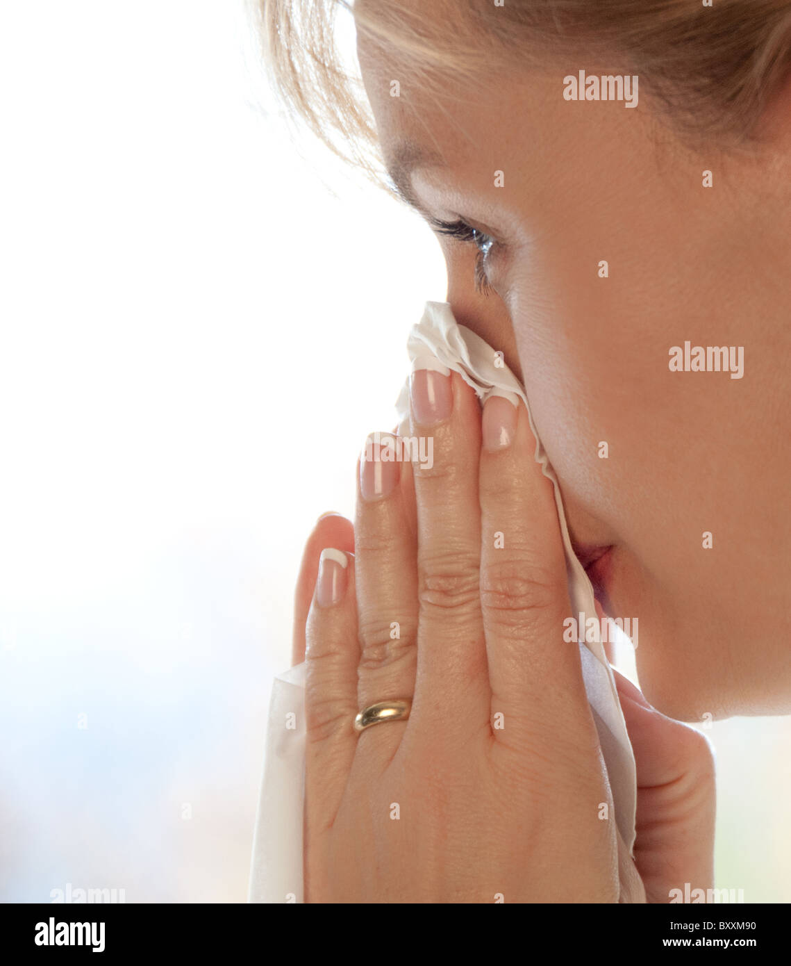 Woman using a tissue to blow her nose Stock Photo - Alamy