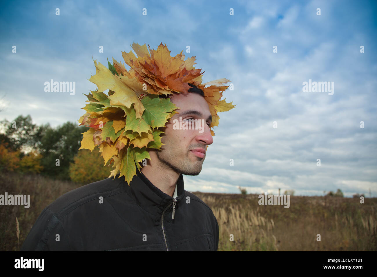The young man with a wreath on a head, twisted from yellow leaves of a ...