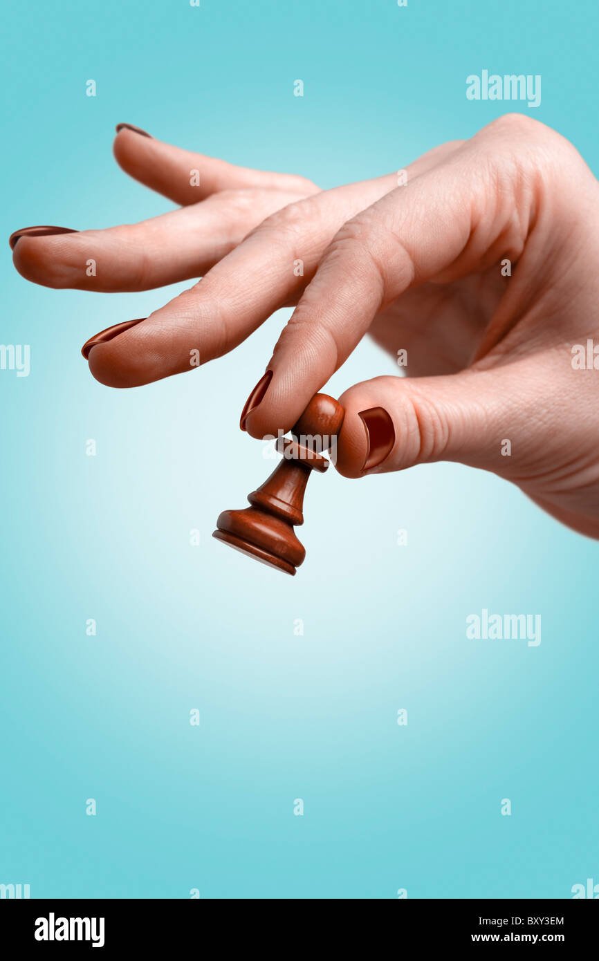 Woman's hand holding chess pawn on blue background Stock Photo - Alamy