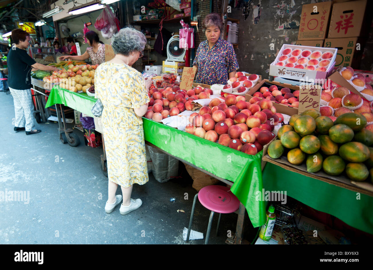 A woman buys fruit seller at a fruit market in central Taipei stands ...