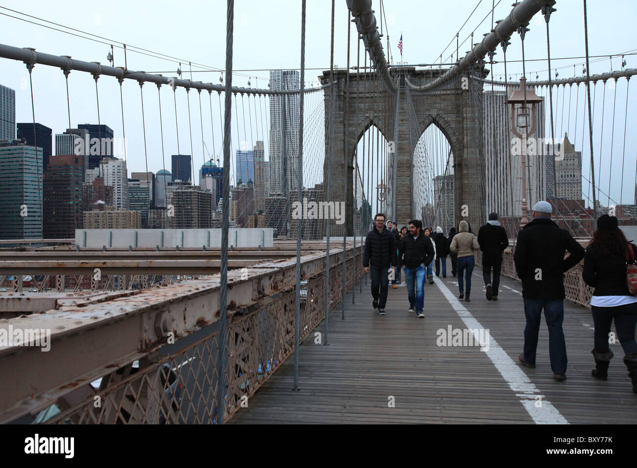 Pedestrians walking on Brooklyn bridge walkway with Manhattan in the ...