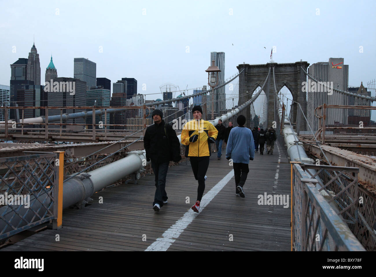 Pedestrians and a runner on Brooklyn bridge walkway with Manhattan in ...