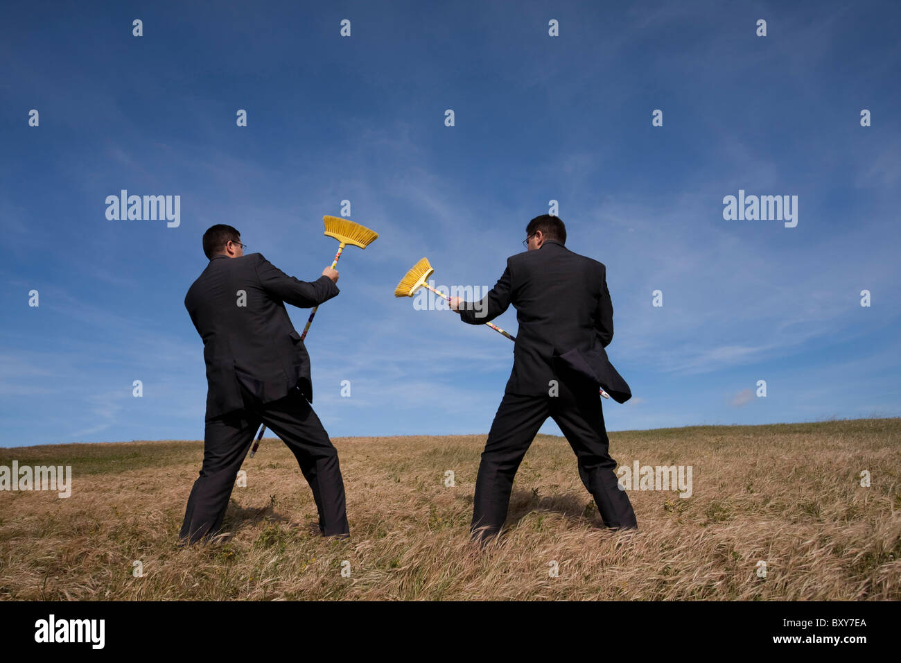two businessman at the field fighting with brooms Stock Photo - Alamy