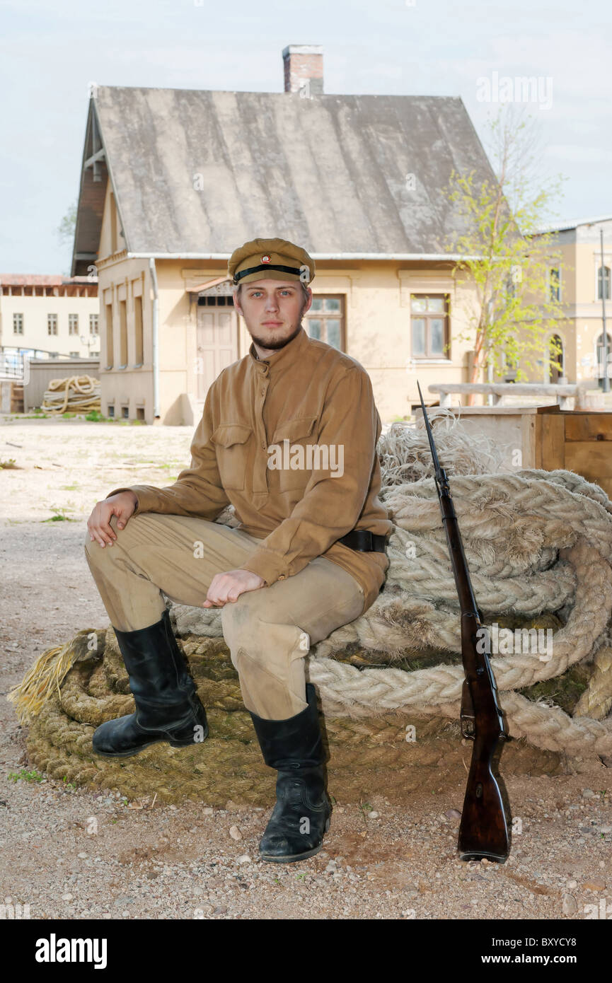 Soldier with a gun in uniform of World War I, sit down on the rope ...