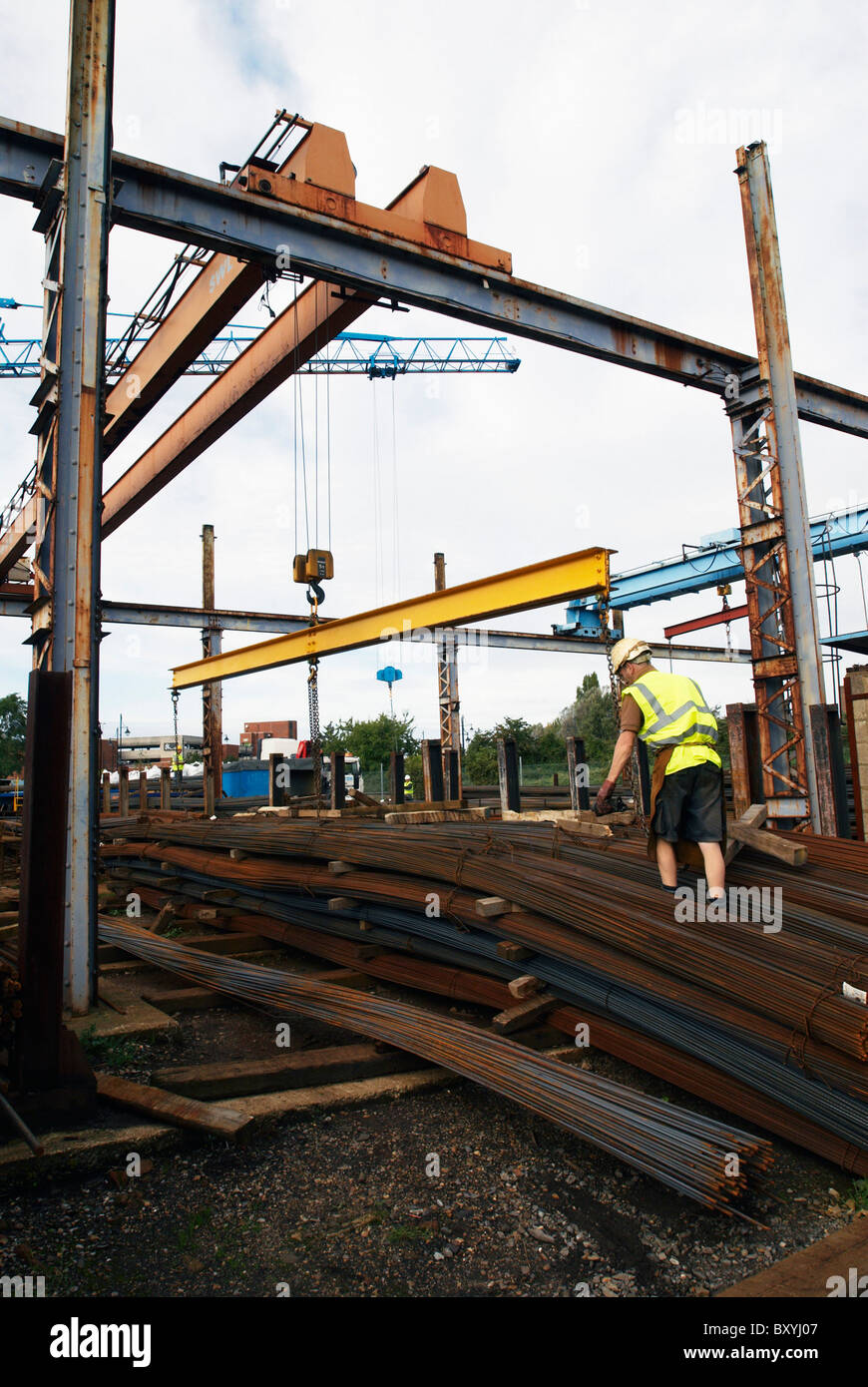 Concrete reinforcement: worker with steel rebar stack in factory yard ...