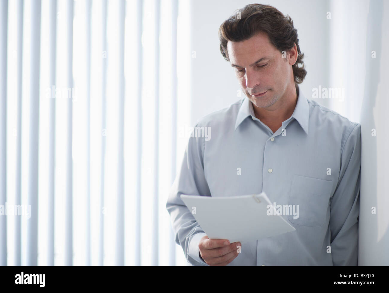 Man in office reading document Stock Photo - Alamy