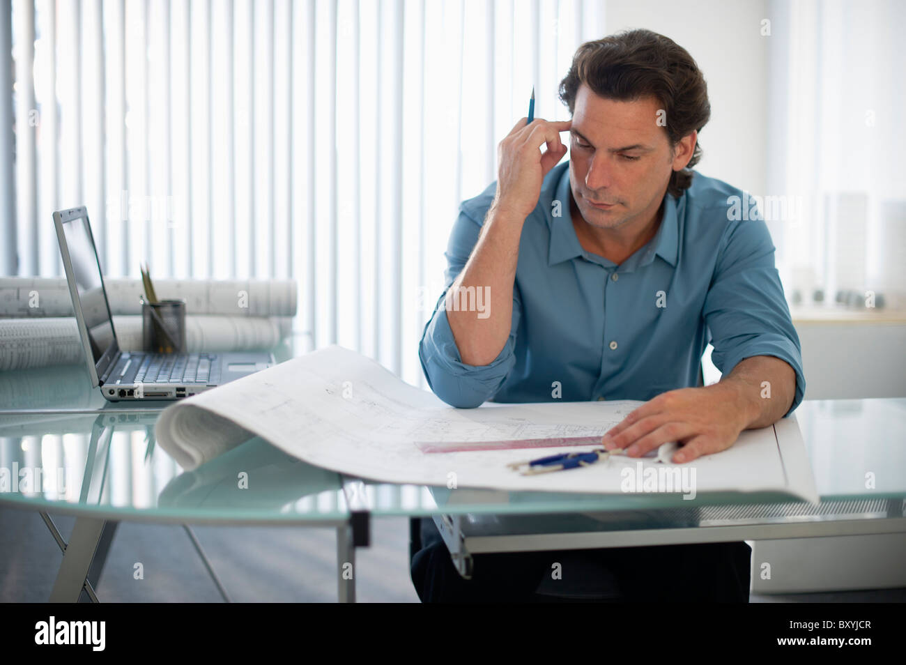 Architect with blueprints in office Stock Photo - Alamy