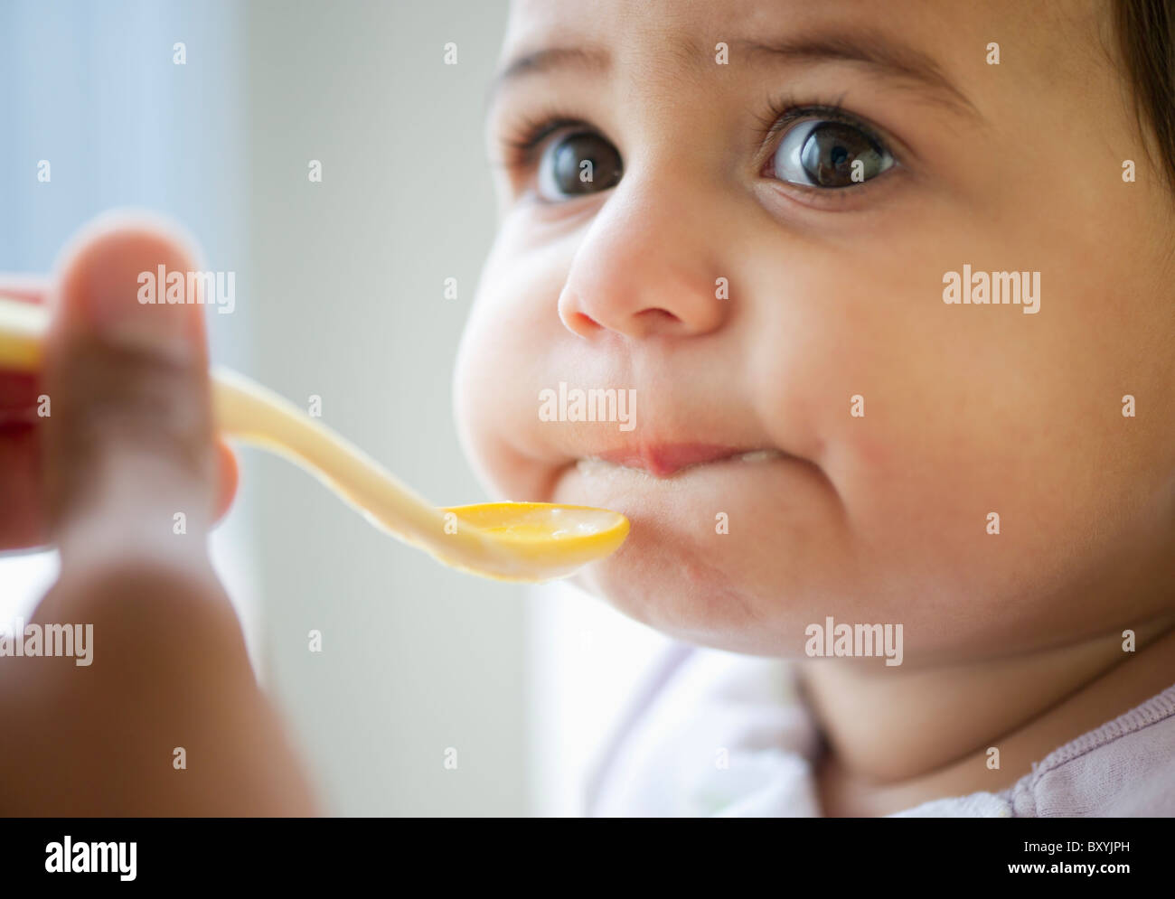 Baby girl eating from plastic spoon Stock Photo - Alamy