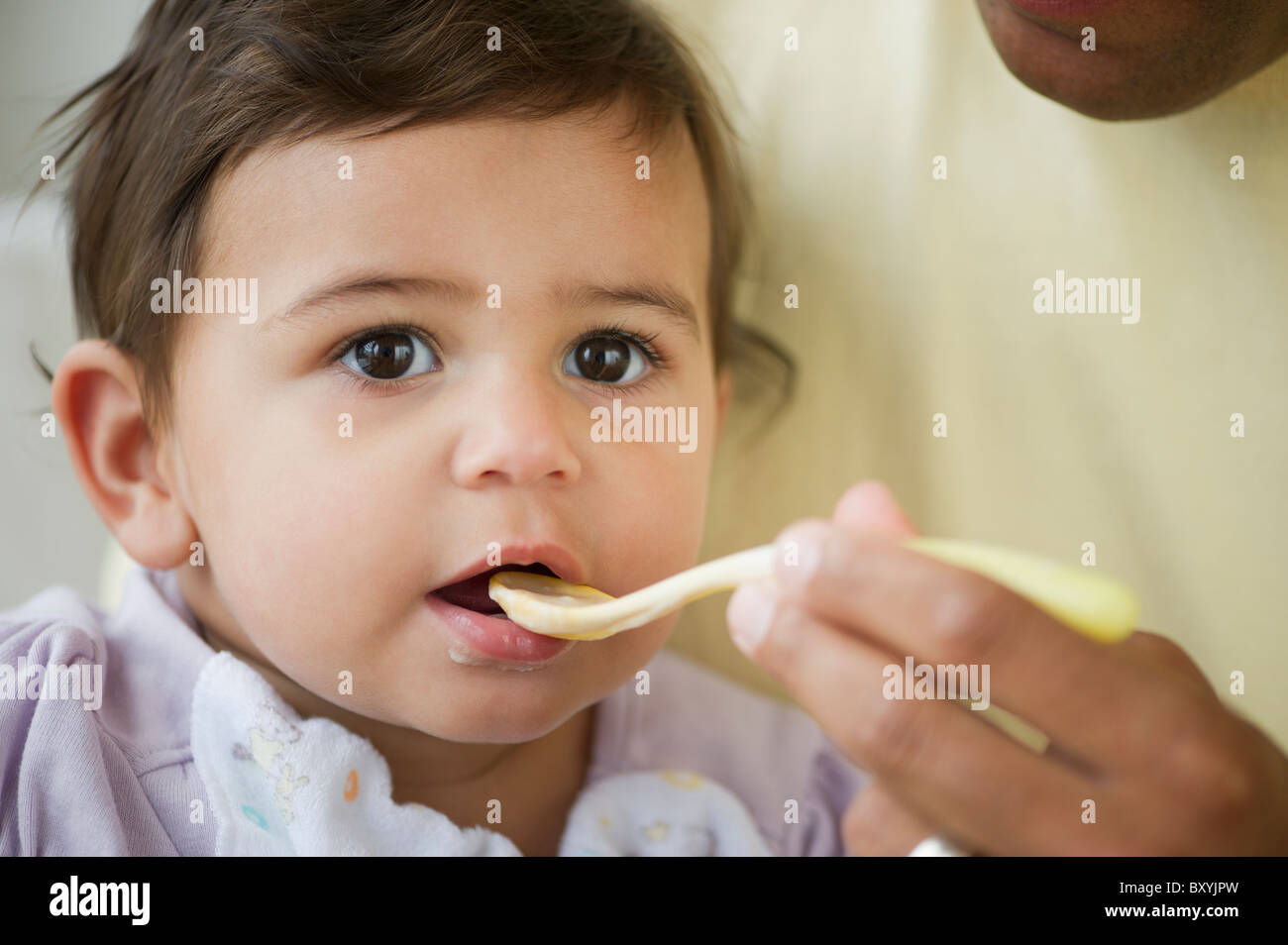 Baby girl eating from plastic spoon Stock Photo - Alamy