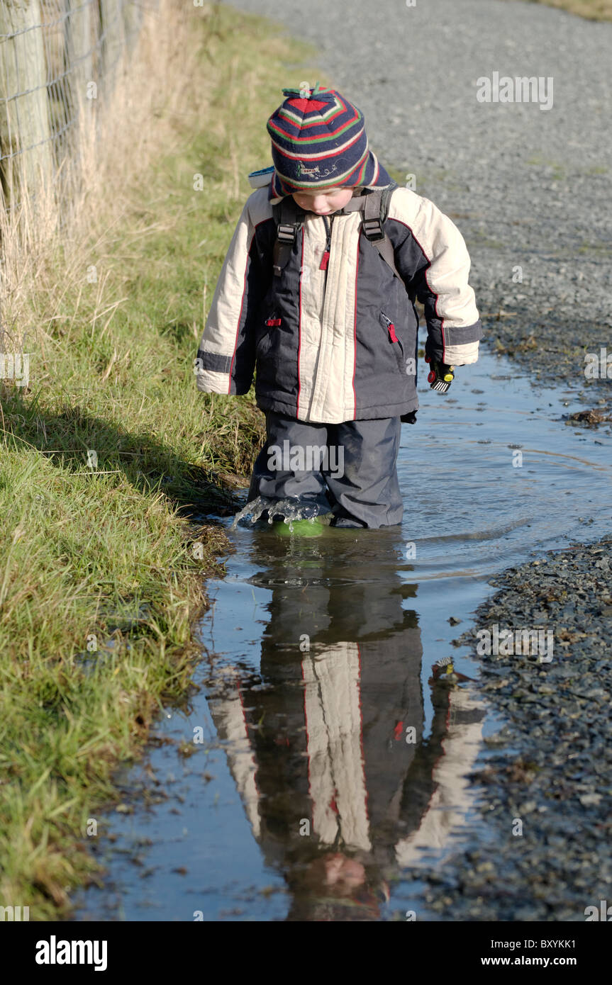 A boy walking through a puddle on a country walk Stock Photo - Alamy