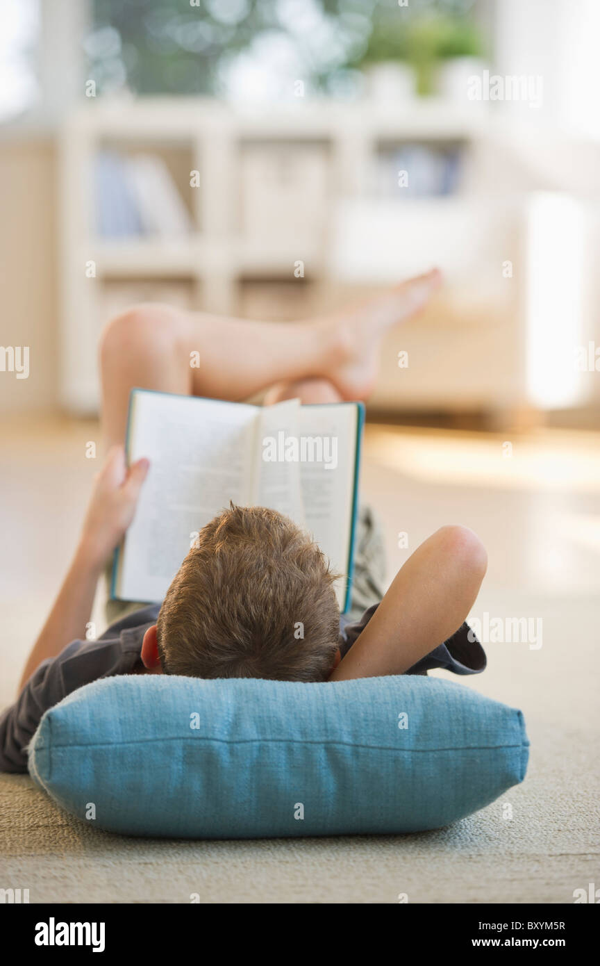 Boy lying on floor and reading book Stock Photo - Alamy
