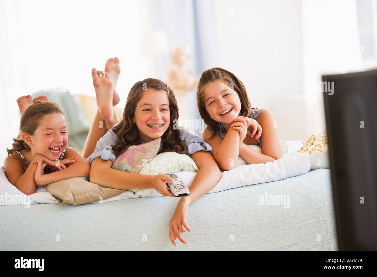 Smiling sisters watching TV Stock Photo - Alamy