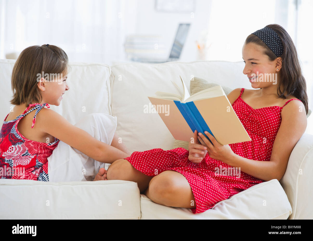 Older sister reading book to younger Stock Photo - Alamy