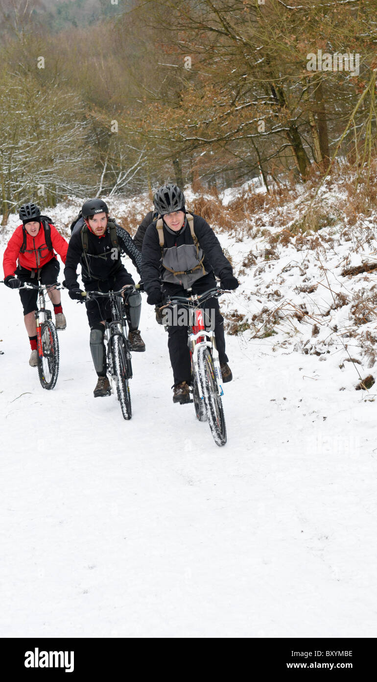 A group of cyclists wearing helmets cycling up a hill in the snow on ...