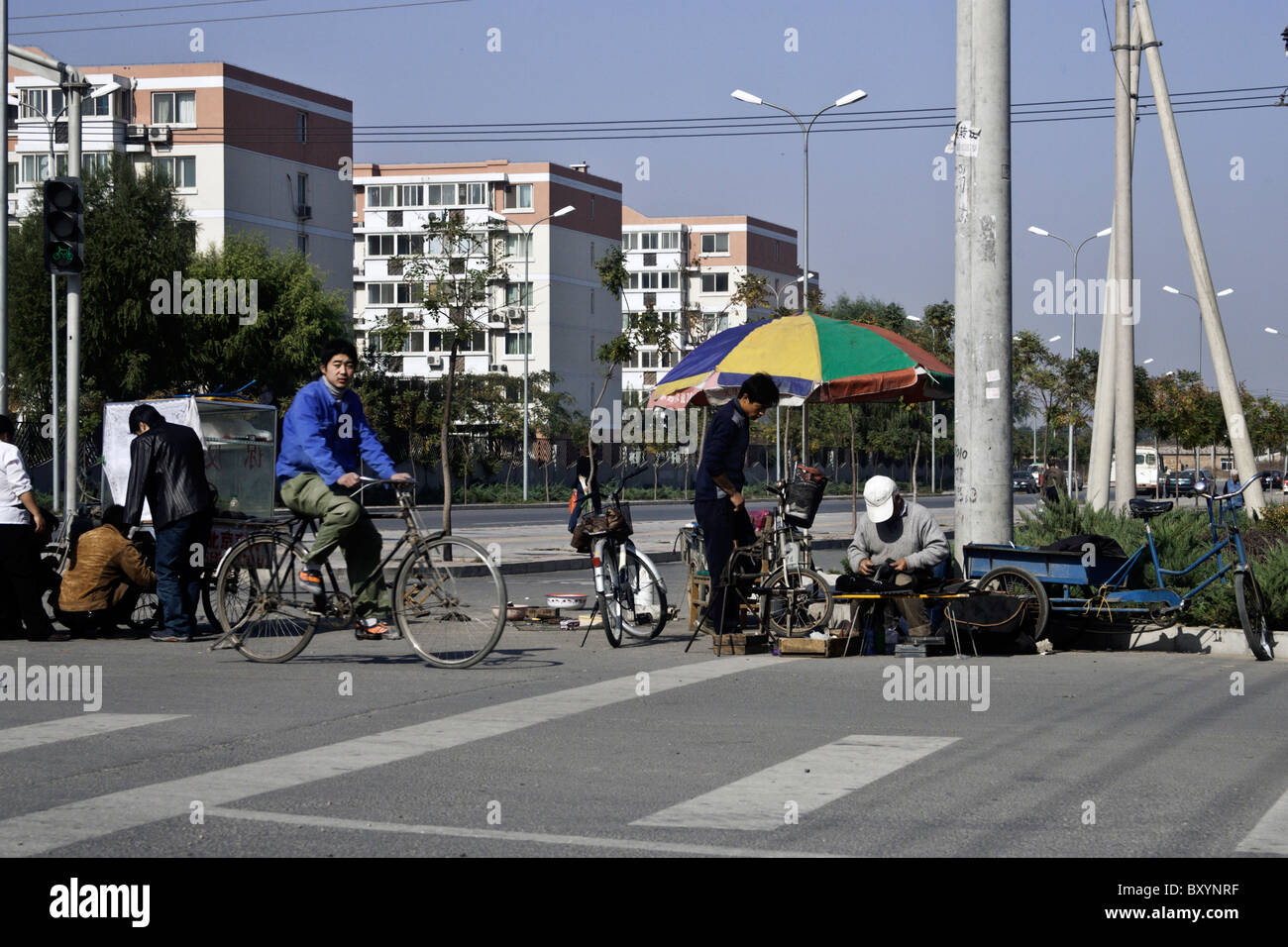 CHINA, BEIJING: Bicycle repair shop under an umbrella on the corner of ...
