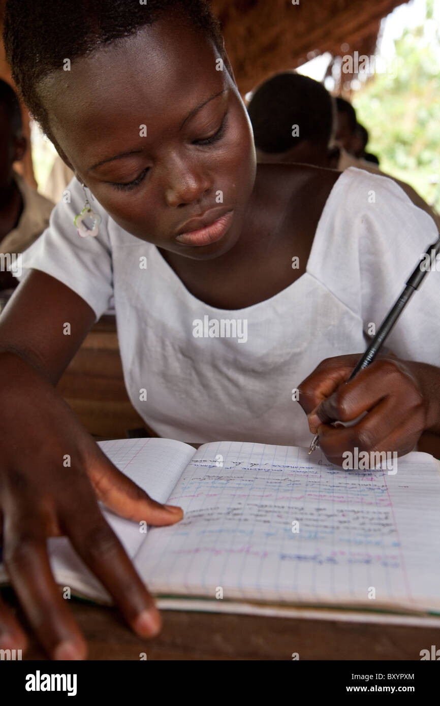 A female African student studies in her thatch roof schoolroom in rural ...