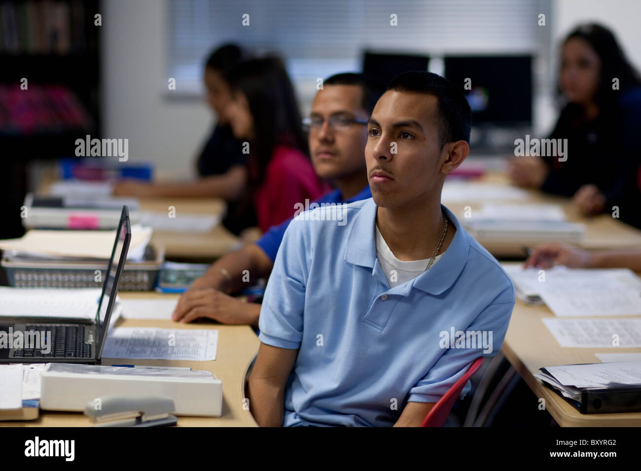 Male and female Hispanic students listen to their teacher in class at ...