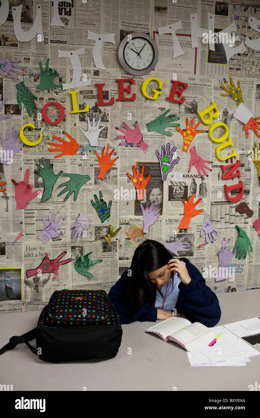 Female high school student sits below classroom wall graphic that ...