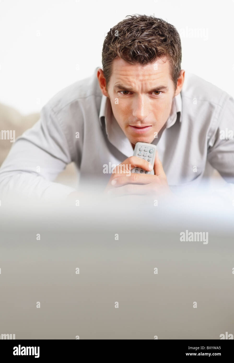 Tense man holding remote control in front of television Stock Photo - Alamy